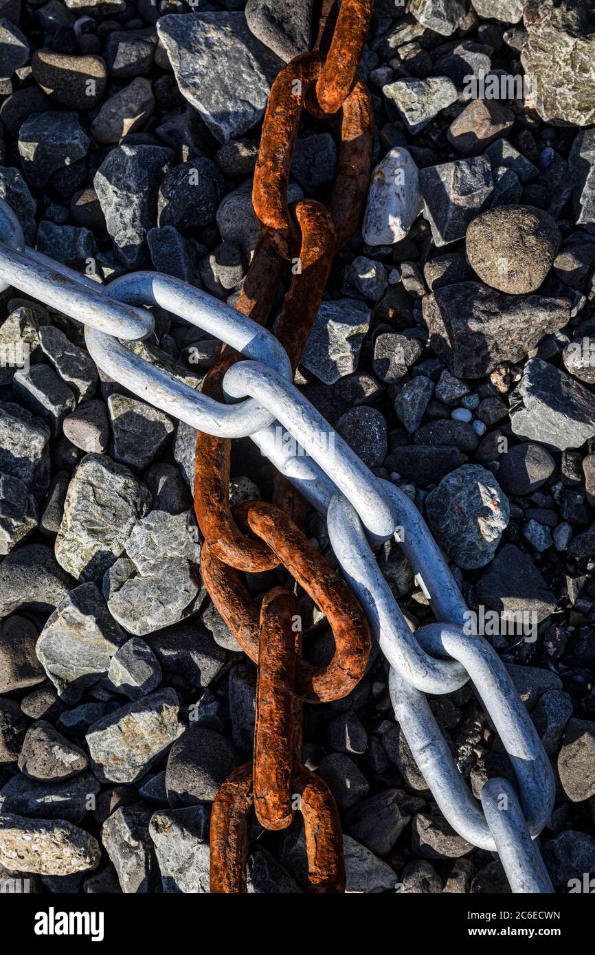 A galvanised chain overlays a rusty one on a rocky beach Stock Photo ...