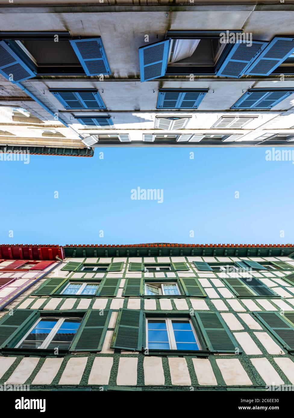 Looking up at old building facades in Bayonne, France. Windows with ...