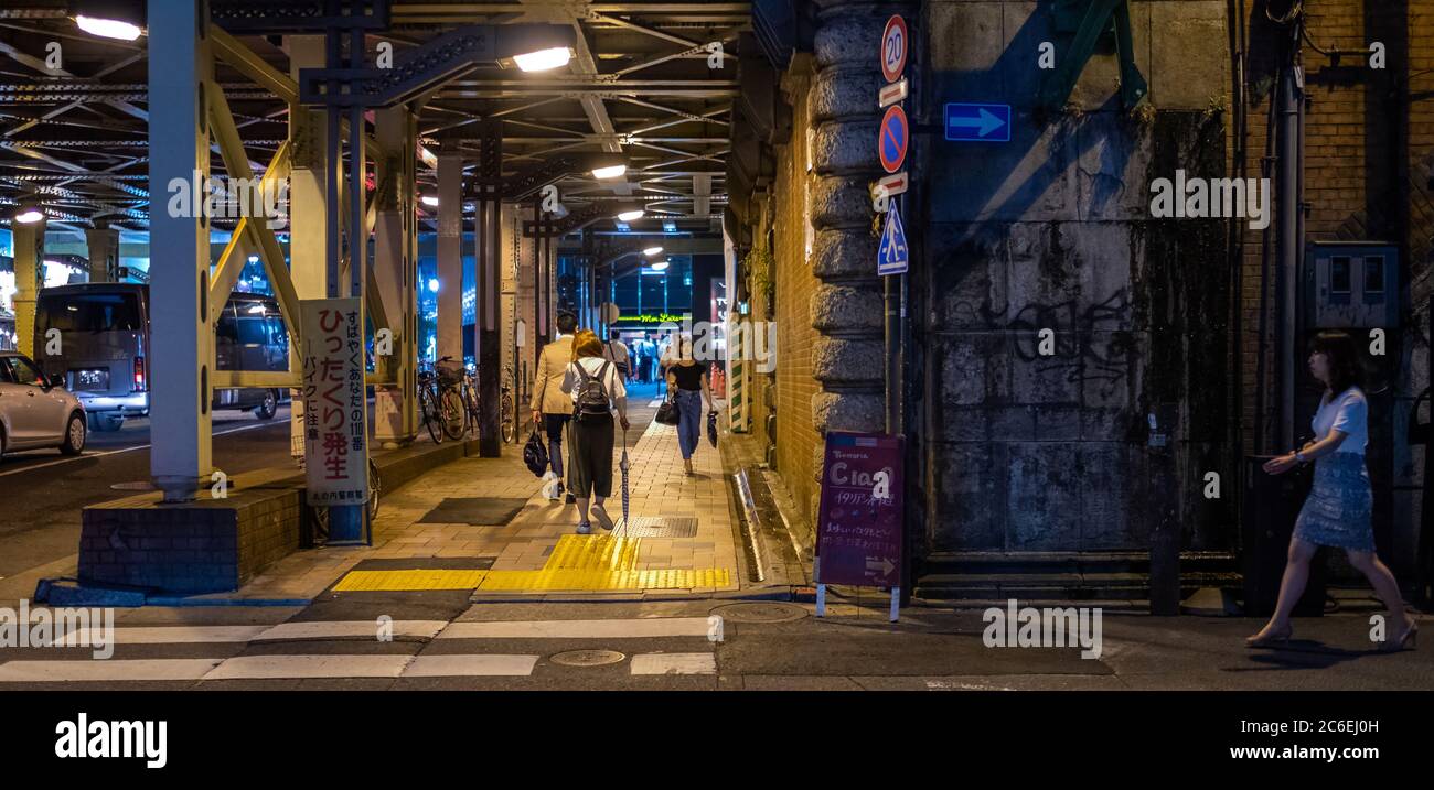 People walking under a rail bridge at Yurakucho street, Tokyo, Japan at ...