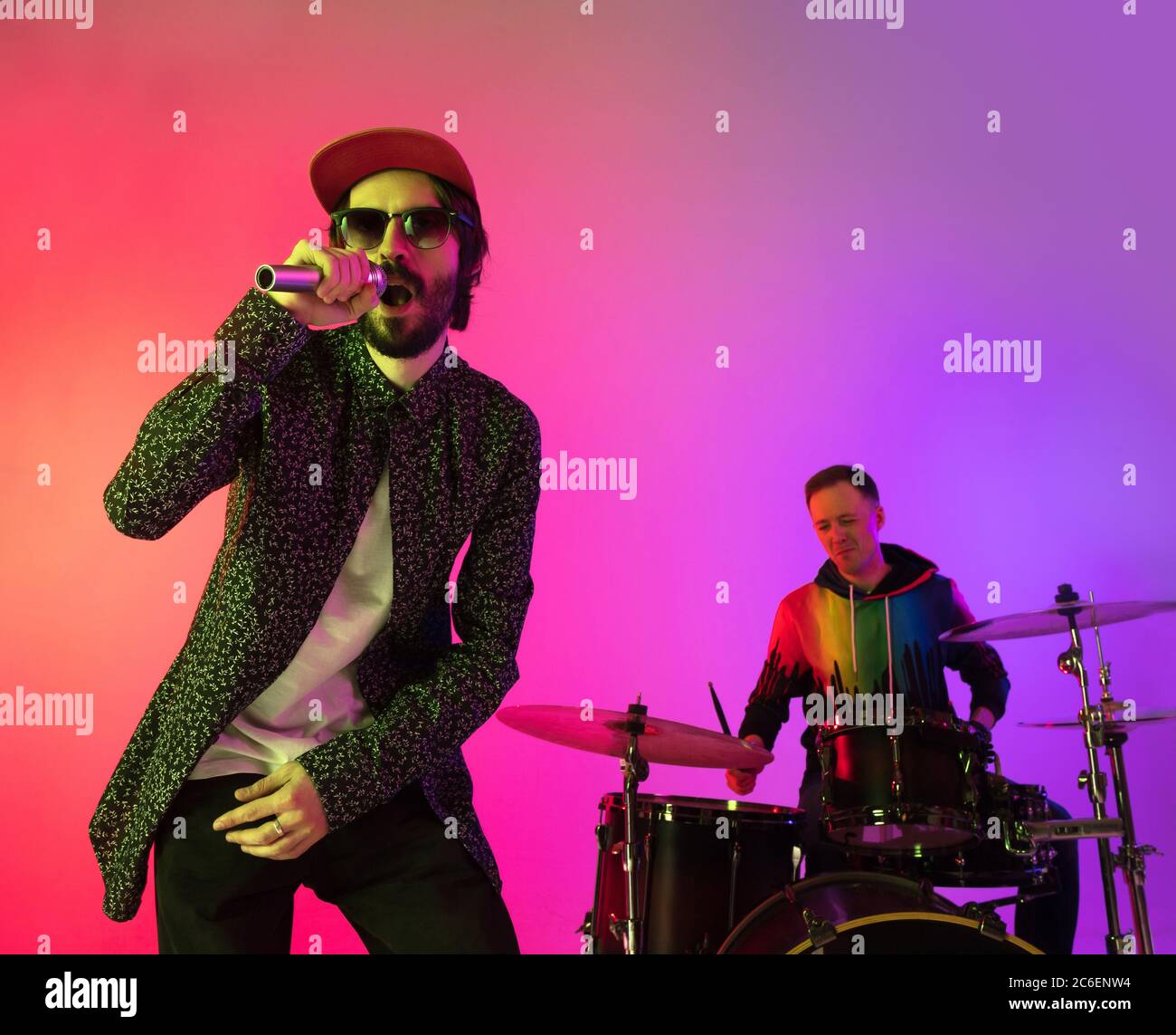 Young caucasian inspired music band performing on gradient colored ...