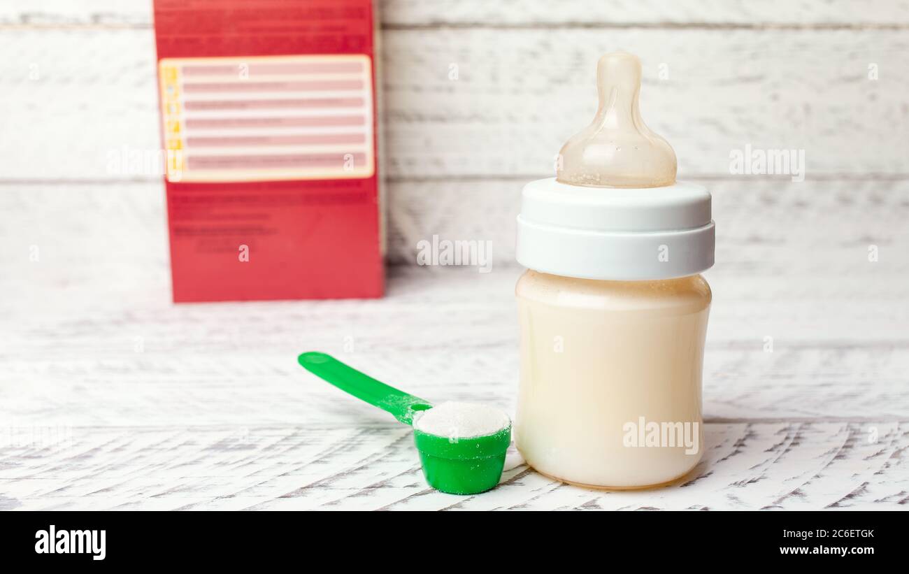 Baby bottle with milk formula on a white wooden background with empty ...