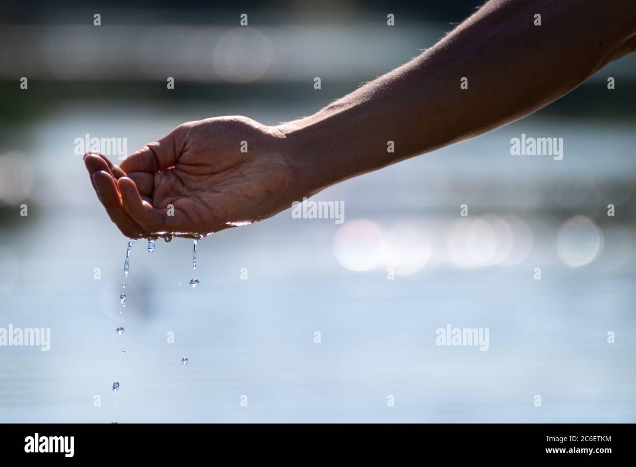 Hand holding sea river water. Pure water in hand drops dropping into ...