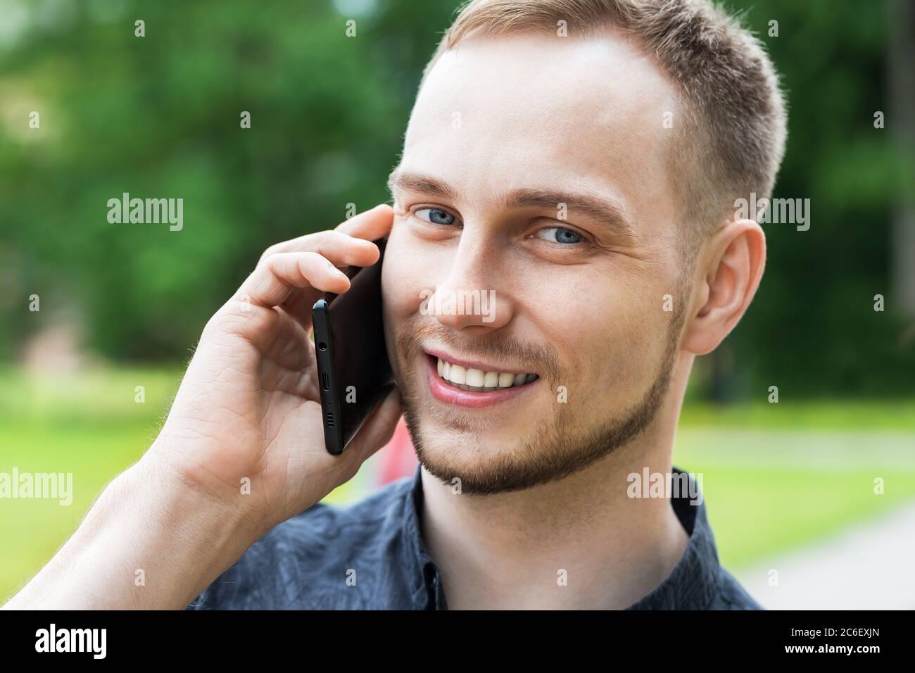 Portrait of handsome young male walking in the Park and talking on ...