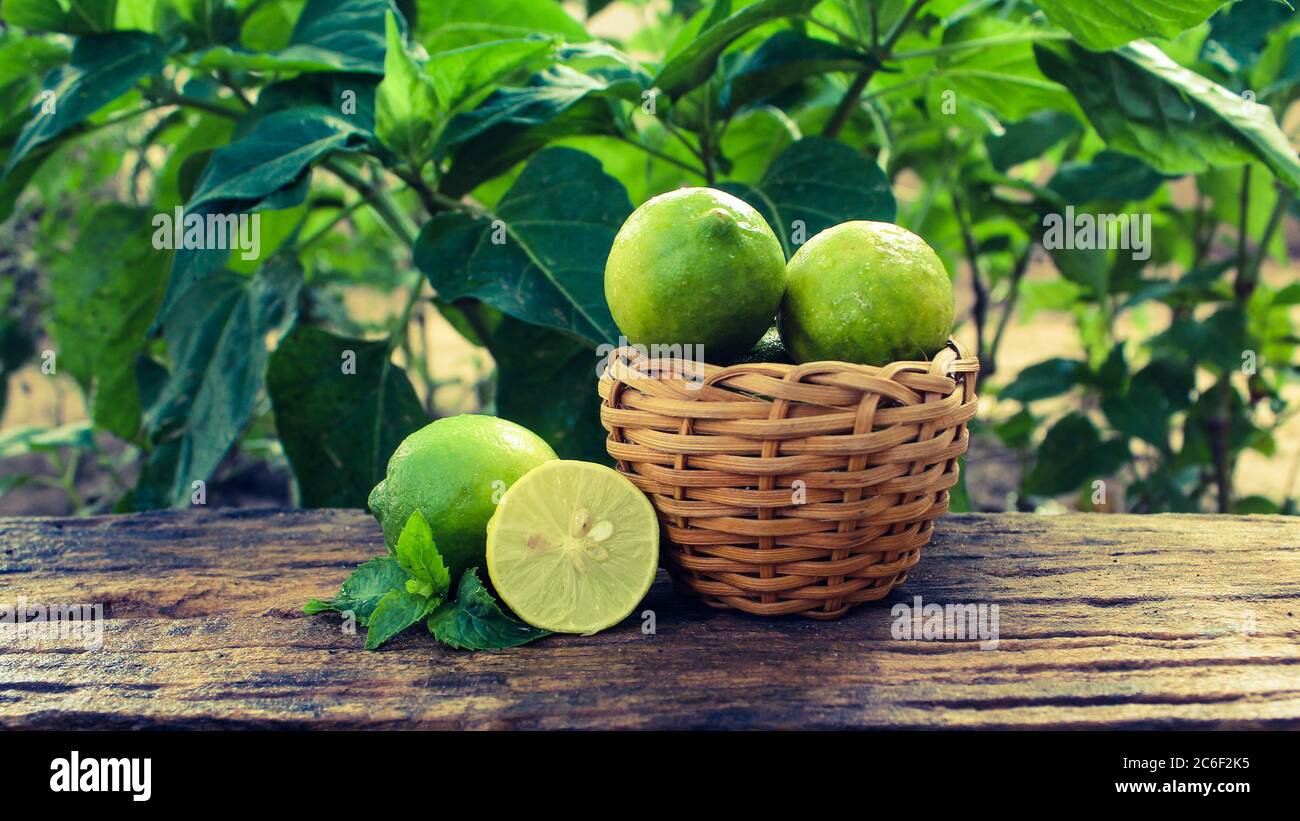Basket full of lemons and half cut lemon on a wooden table Stock Photo ...