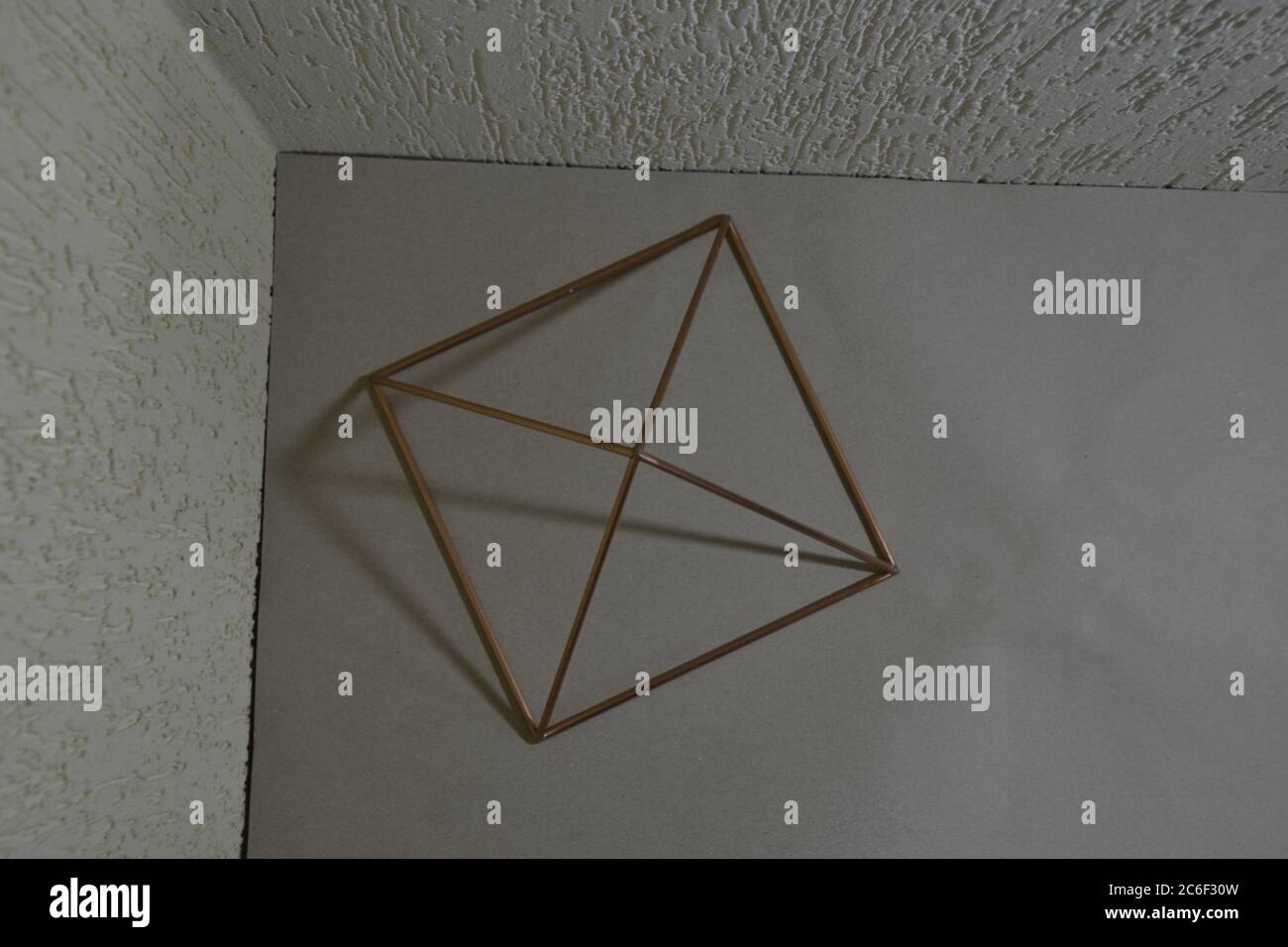 Copper pyramid, top view, white wall to the side and travertine marble ...