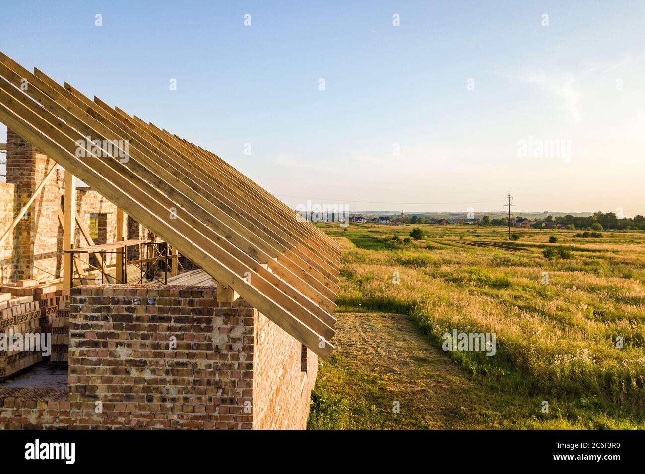 Unfinished brick house with wooden roof structure under construction ...