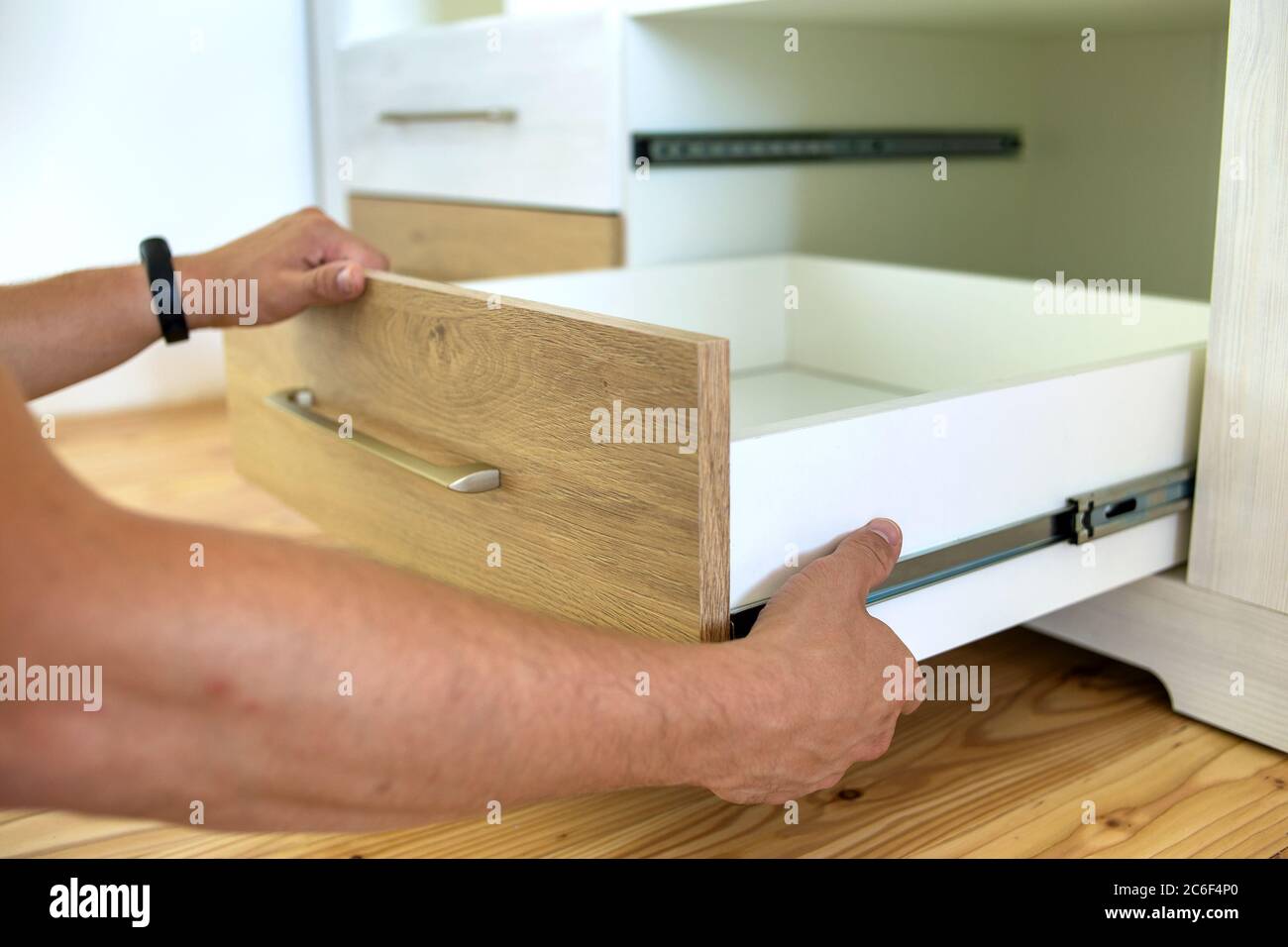 Close up of carpenter hands installing wooden drawer on sliding skids ...