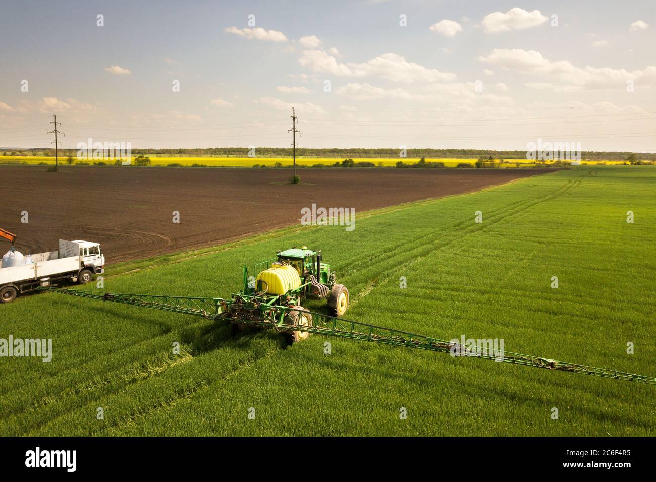 Tractor spraying chemical pesticides with sprayer on the large green ...