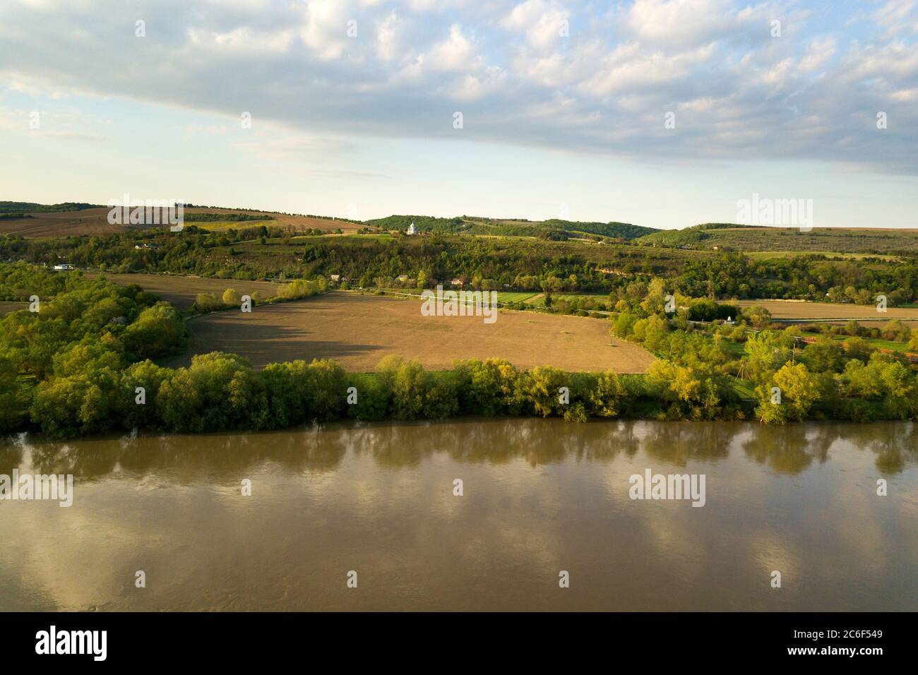 Aerial view of bright river flowing through green meadows in spring ...