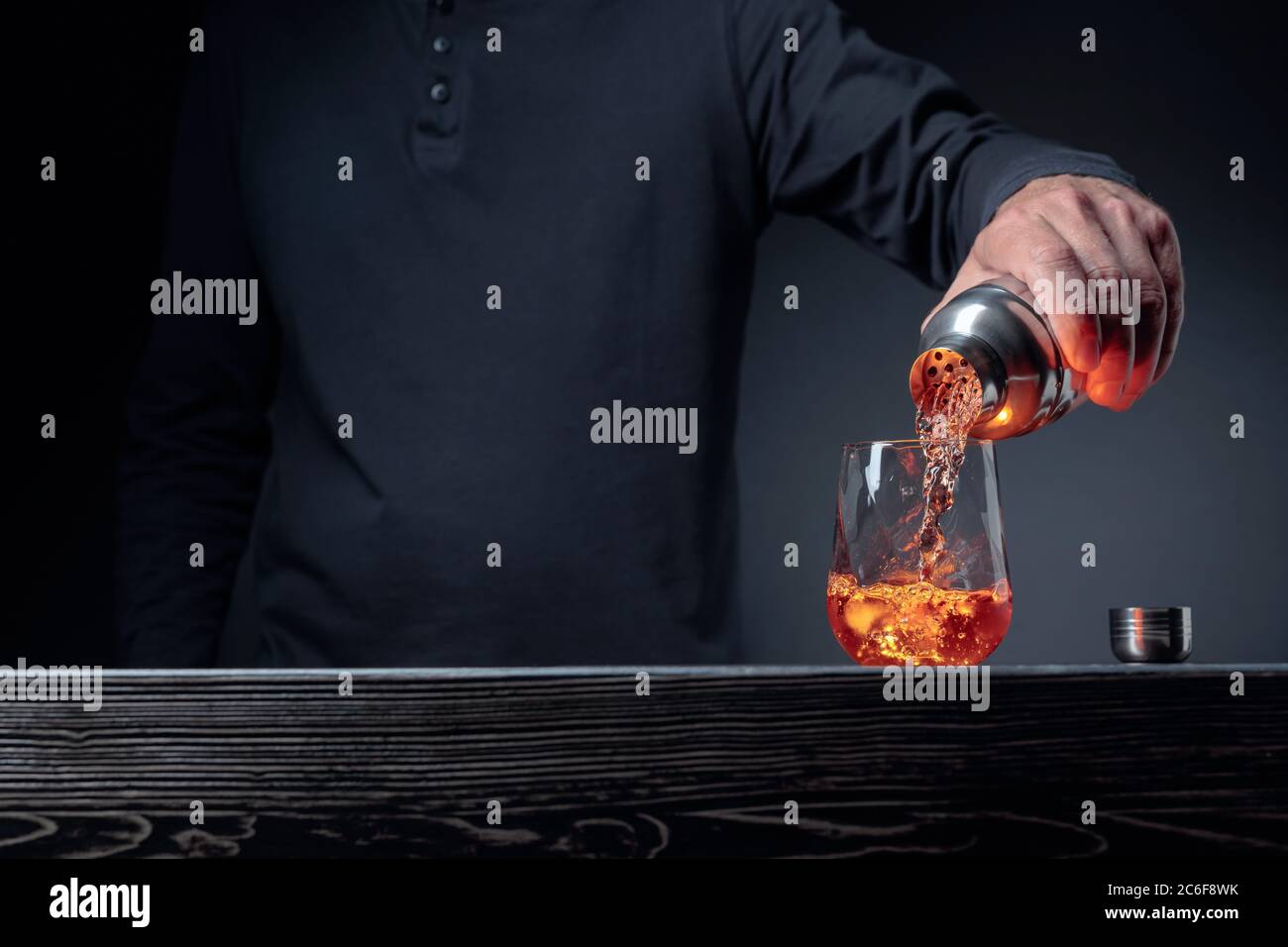 Bartender pouring cocktail into glass at bar counter. Alcoholic drink ...