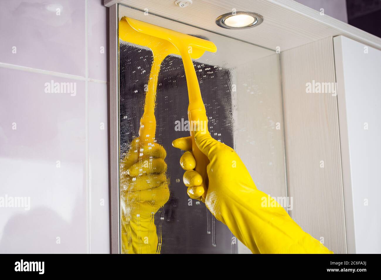 Maid with rubber glove cleaning tap and sink. Housekeeping scrubbing ...