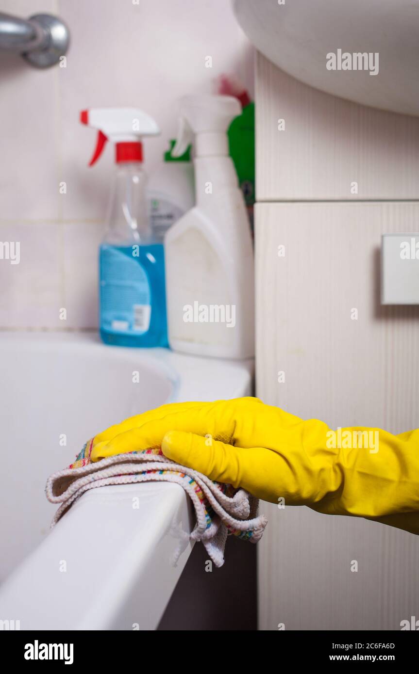 Maid with rubber glove cleaning tap and sink. Housekeeping scrubbing ...