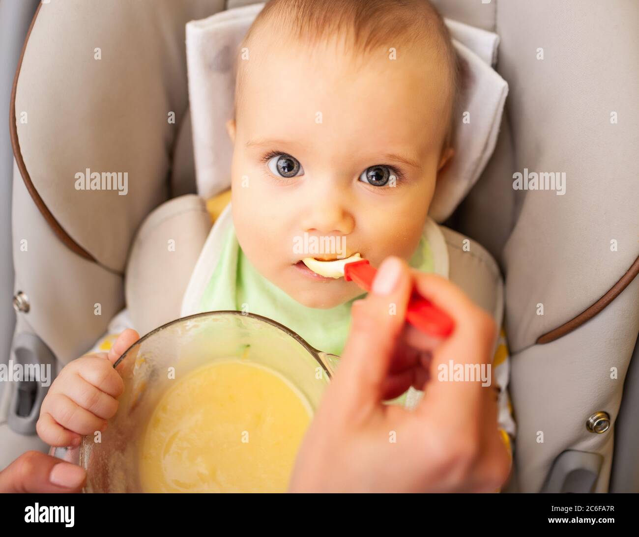 Unidentified mothers hand carefully feeds a cute healthy newborn girl ...
