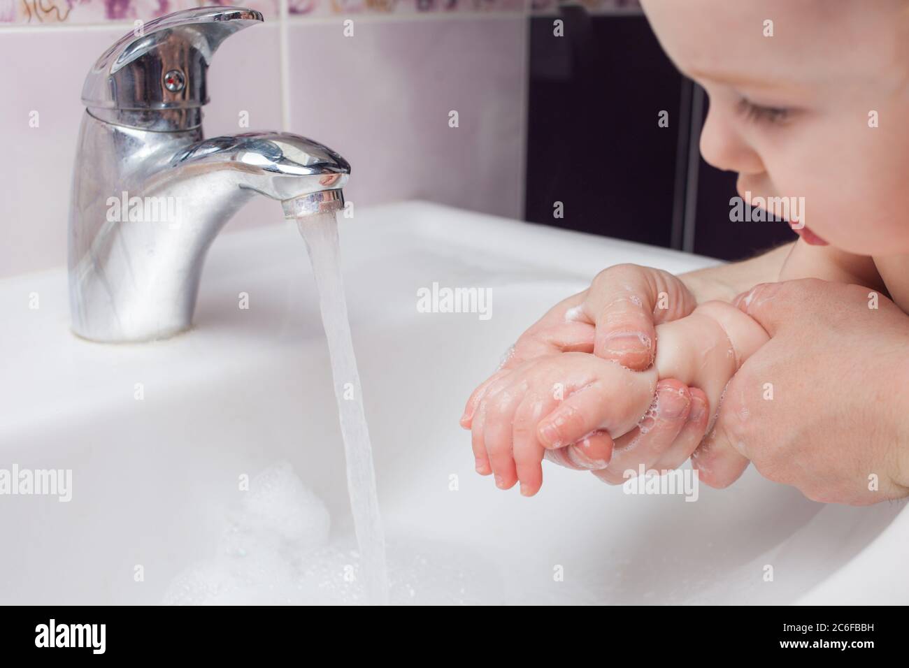 child washes hands in sink. jet of water from tap. Disinfection of ...