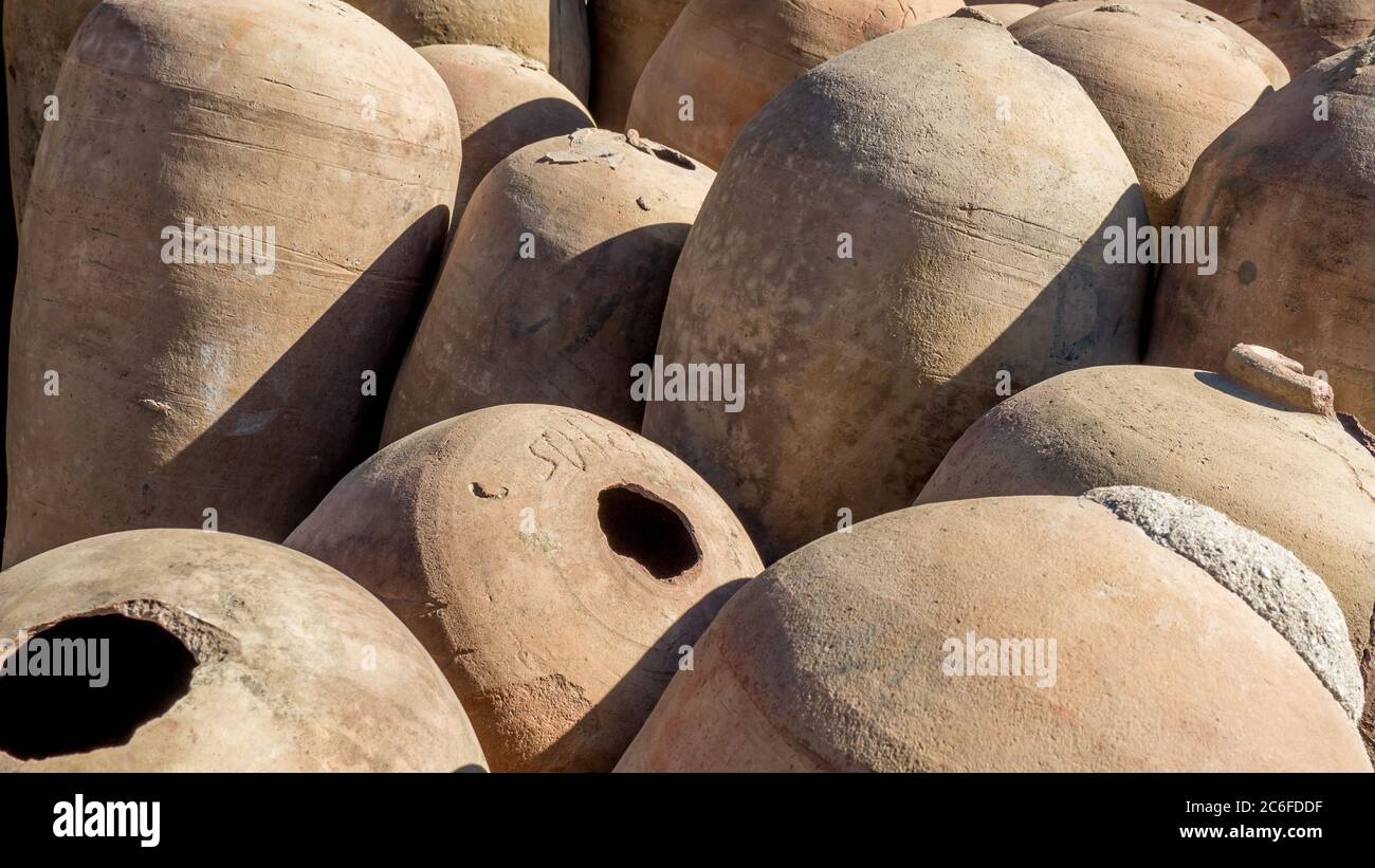 horizontal close-up of a group of aged wine pitchers made of tone ...