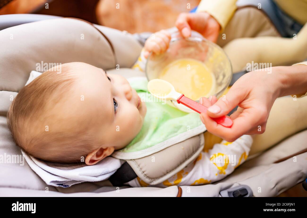 Unidentified mothers hand carefully feeds a cute healthy newborn girl ...