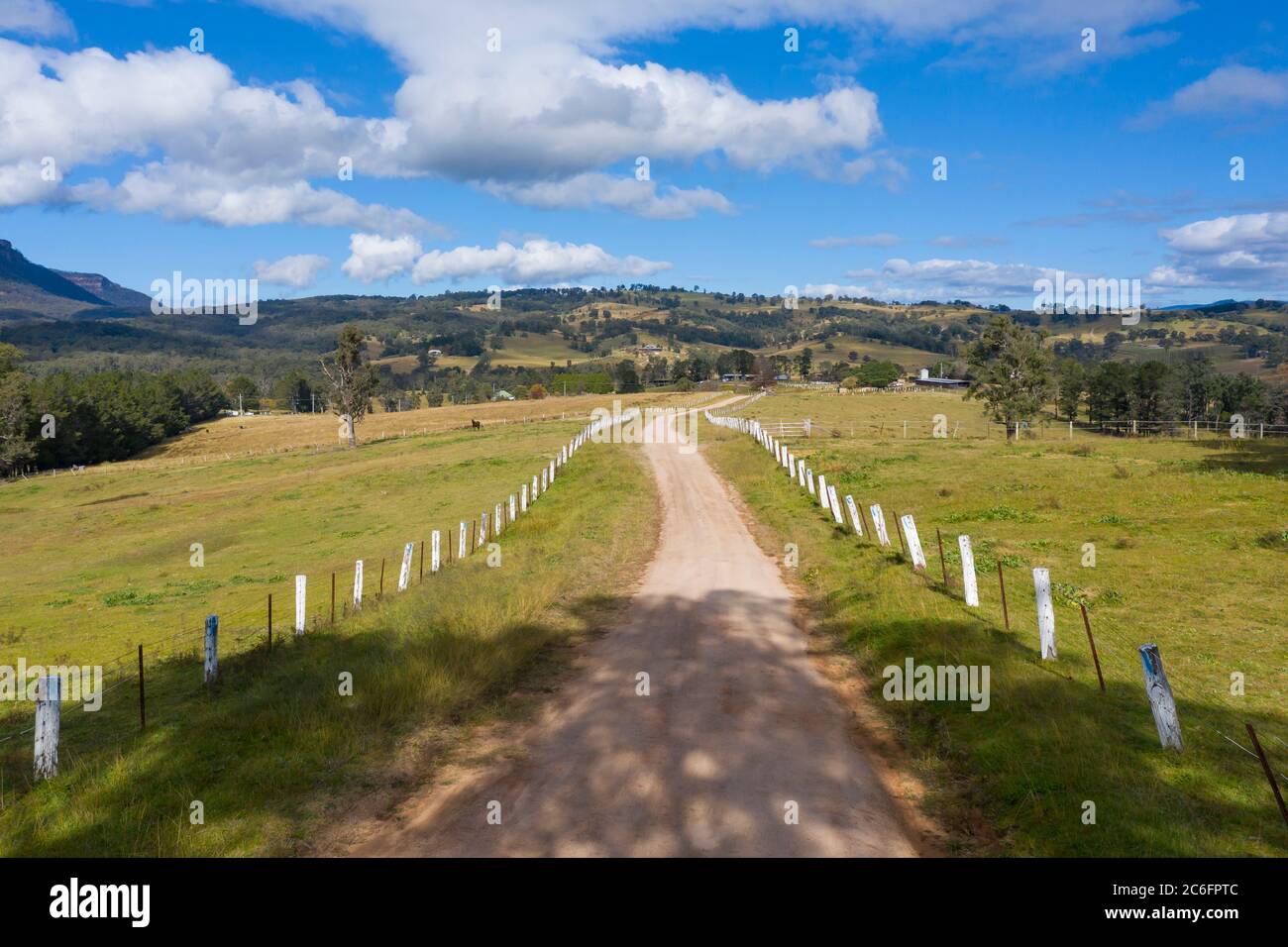 Aerial view of a dirt road with white fence post markers in a green ...