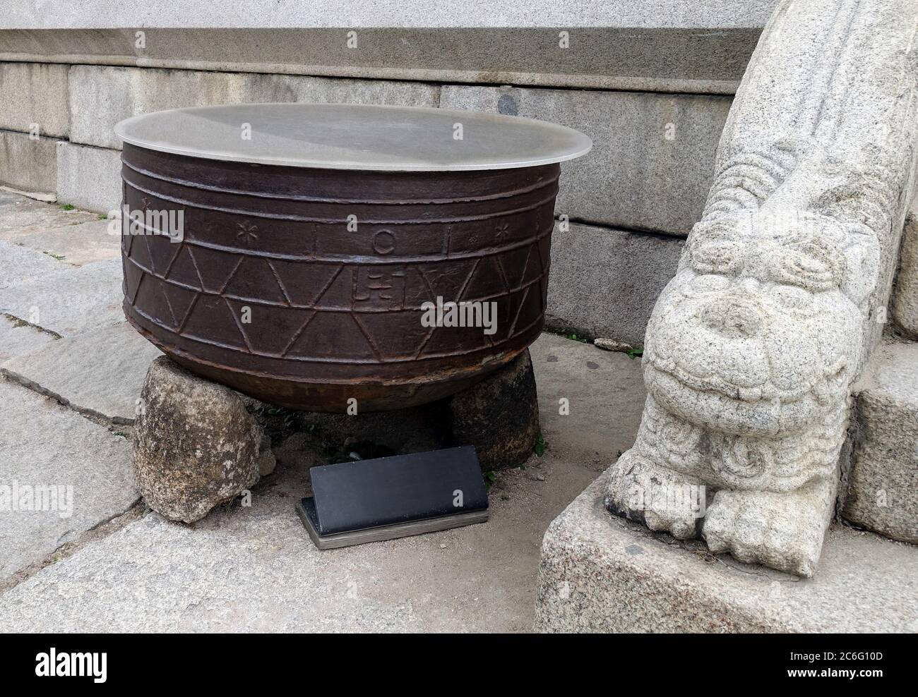 Ancient bronze water pot for fire fighting next to stone statue in ...