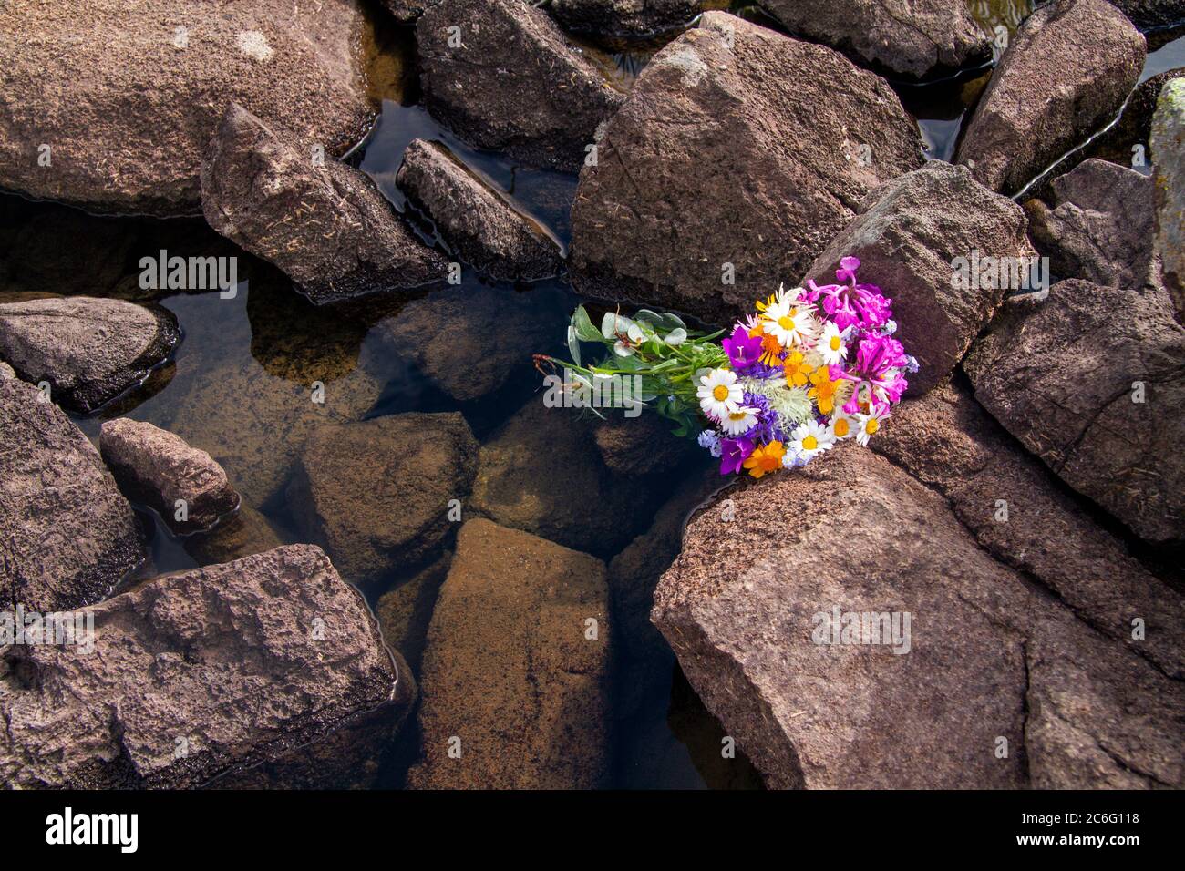 Water among basalt rock fragments and a bunch of colorful flowers in ...