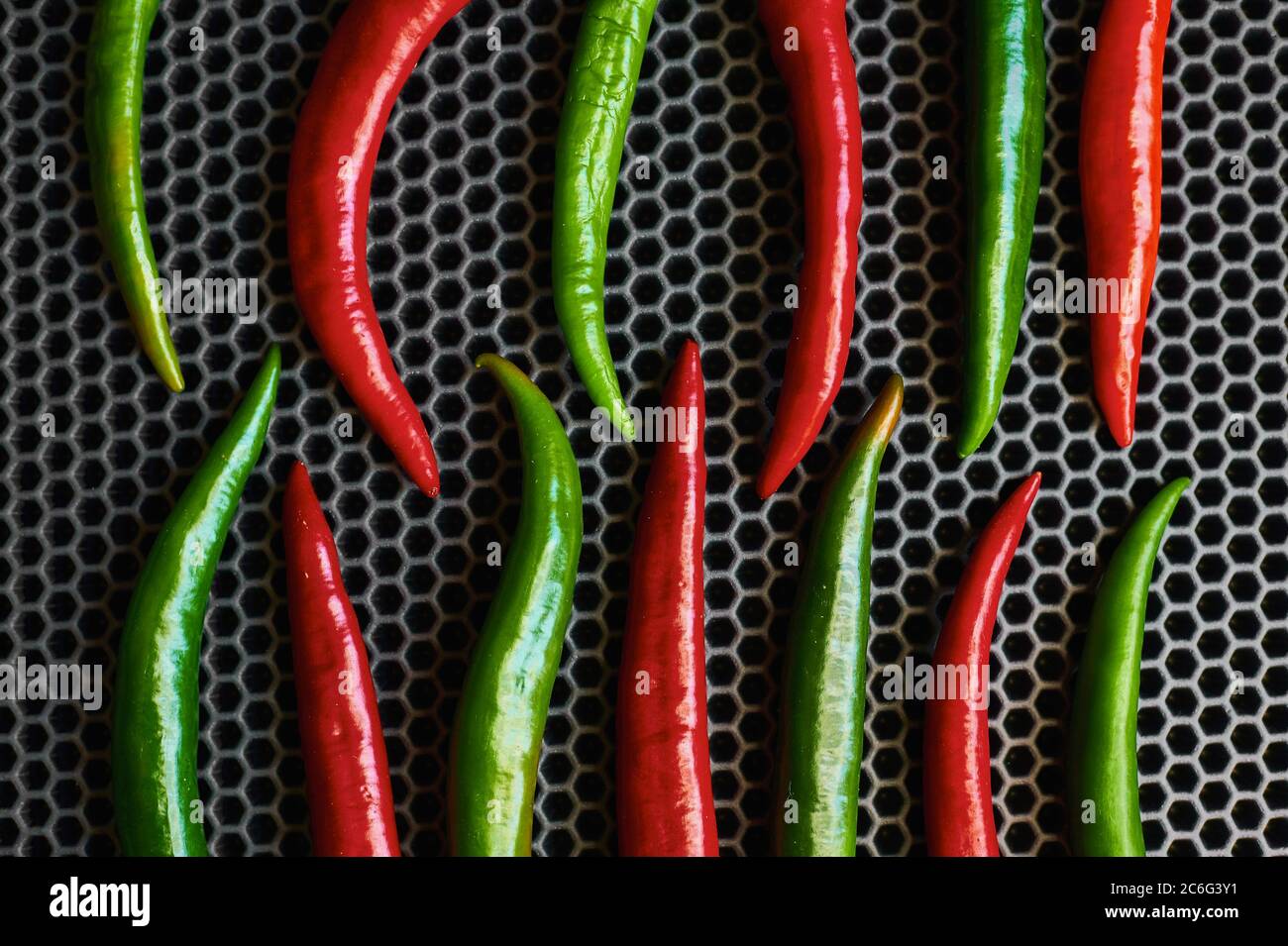 red and green hot chili pepper close-up against a dark background ...