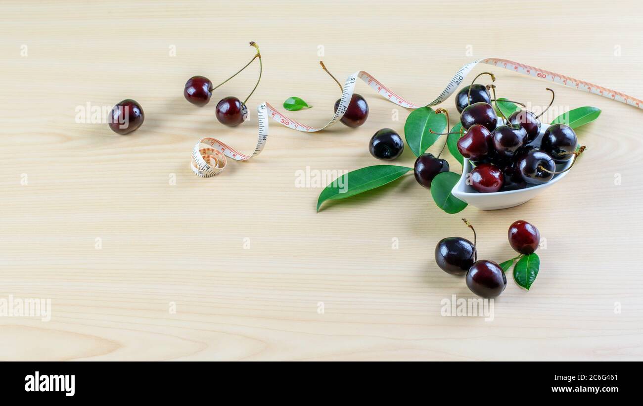 Dosing tape and ripe fresh cherries on the wooden table. Healthy eating ...