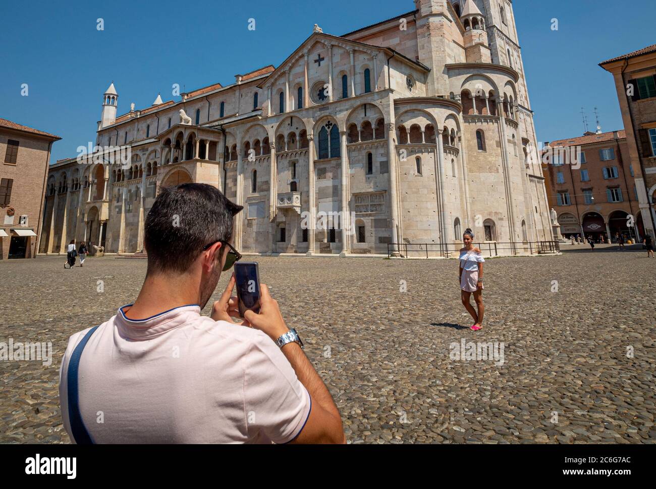 Man taking a photo in front of Duomo di Modena seen from Piazza Grande ...