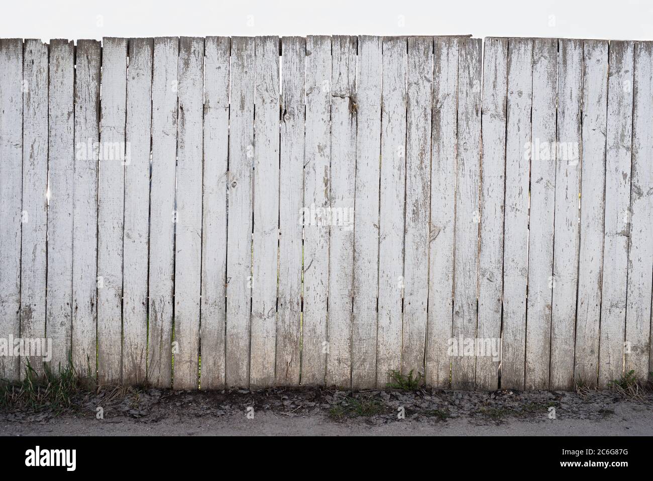 white old fence from boards, peeling paint, uneven fencing texture ...