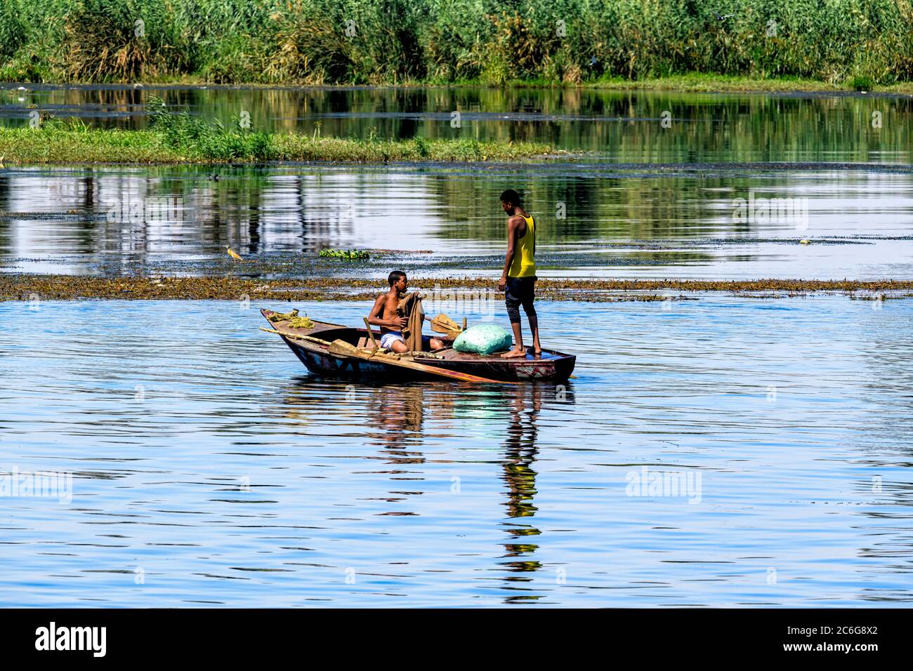 Two young men fishing from a rowing boat, in the early morning on the ...