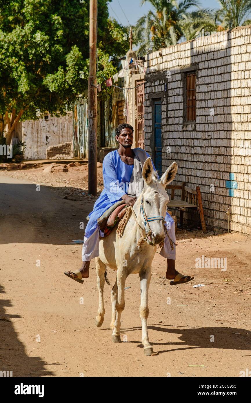 Farmer riding his donkey through the streets of a village on the west ...