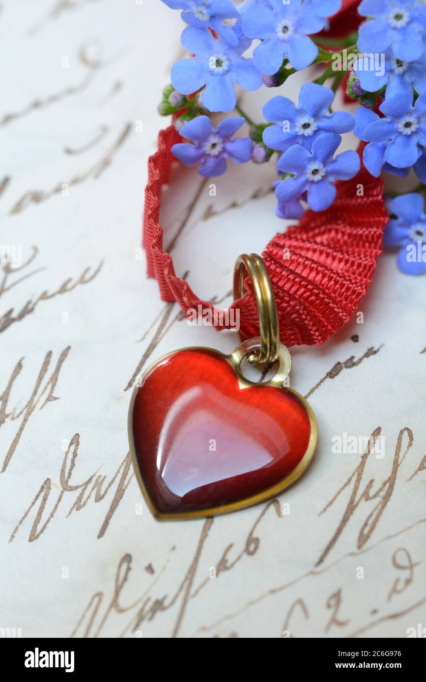 Pendant with heart and forget-me-not on letter paper with old writing ...