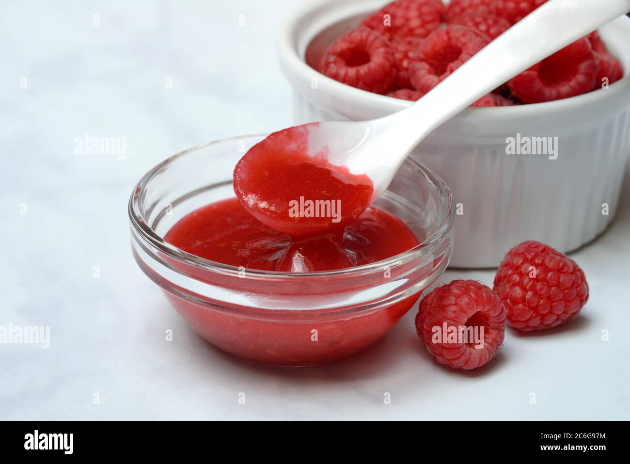 Raspberry sauce, raspberry jam in glass bowl with spoon, raspberries ...