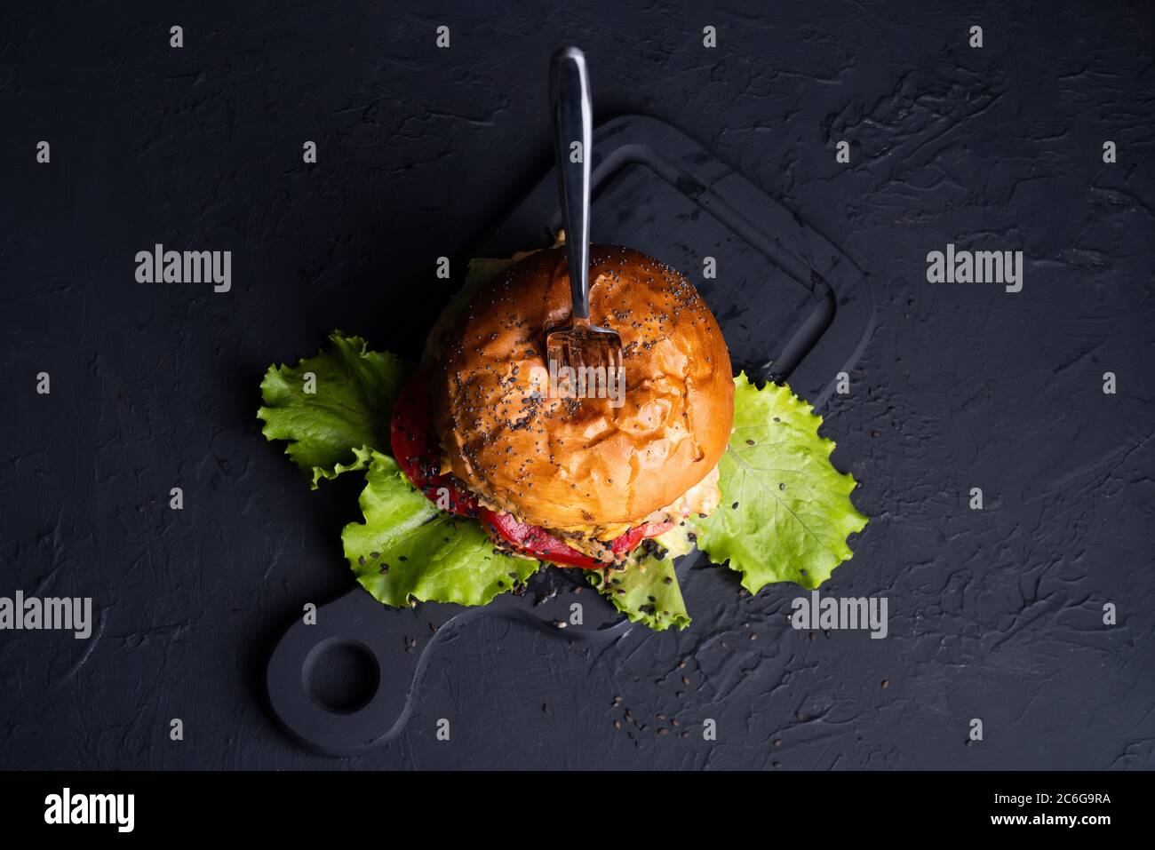 fresh lettuce leaves on sides, black background, top view big burger ...