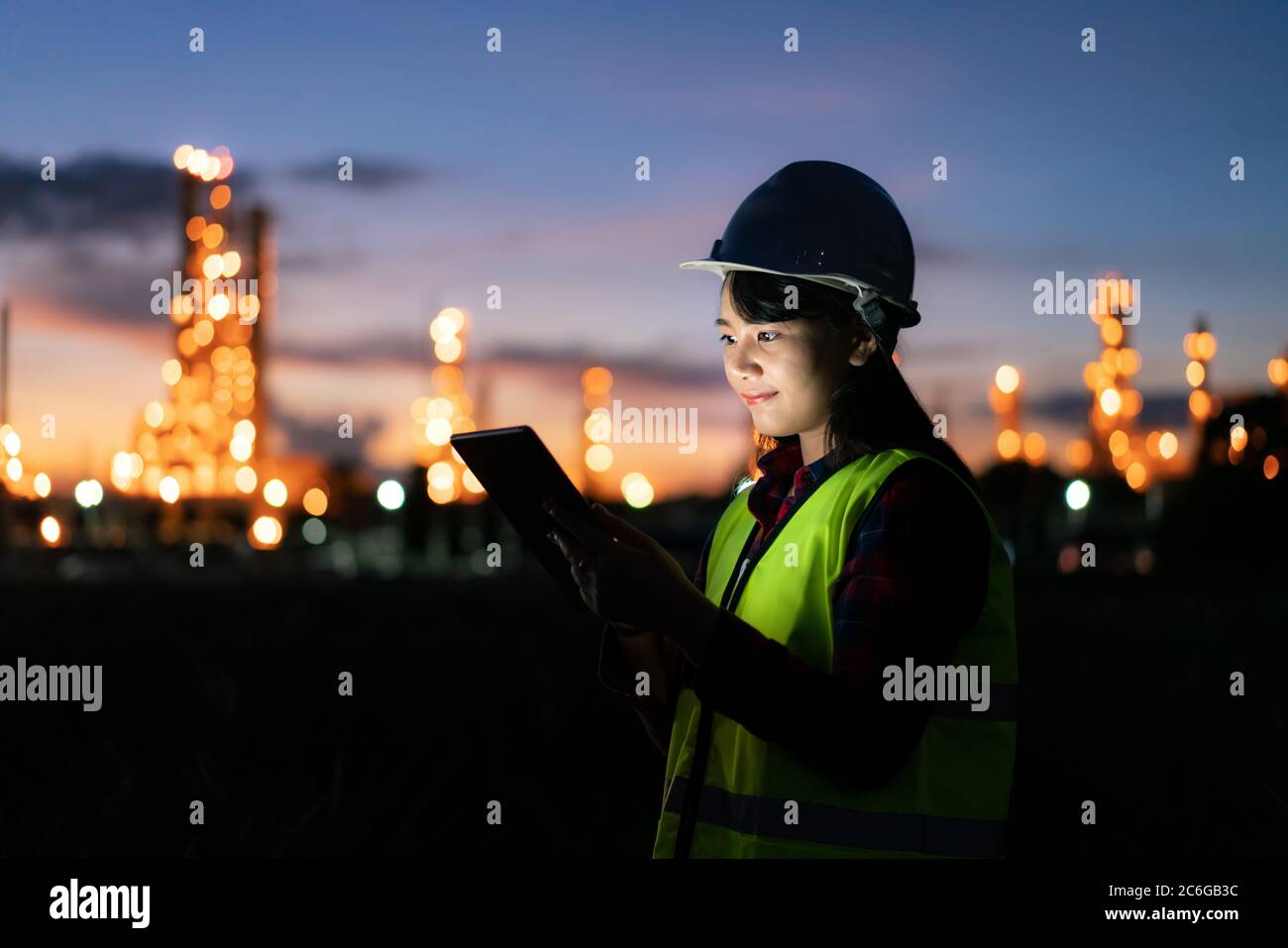 Asian woman petrochemical engineer working at night with digital tablet ...