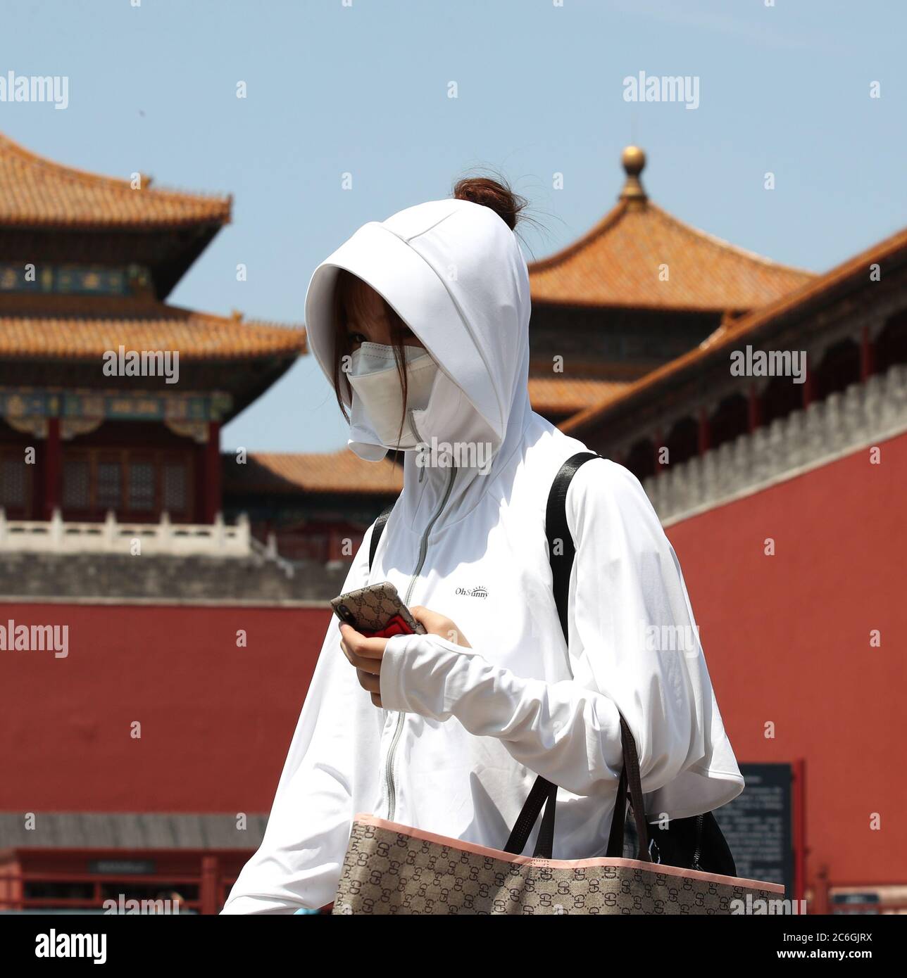 People covered with clothes, unbrella and masks walk under the sun in ...