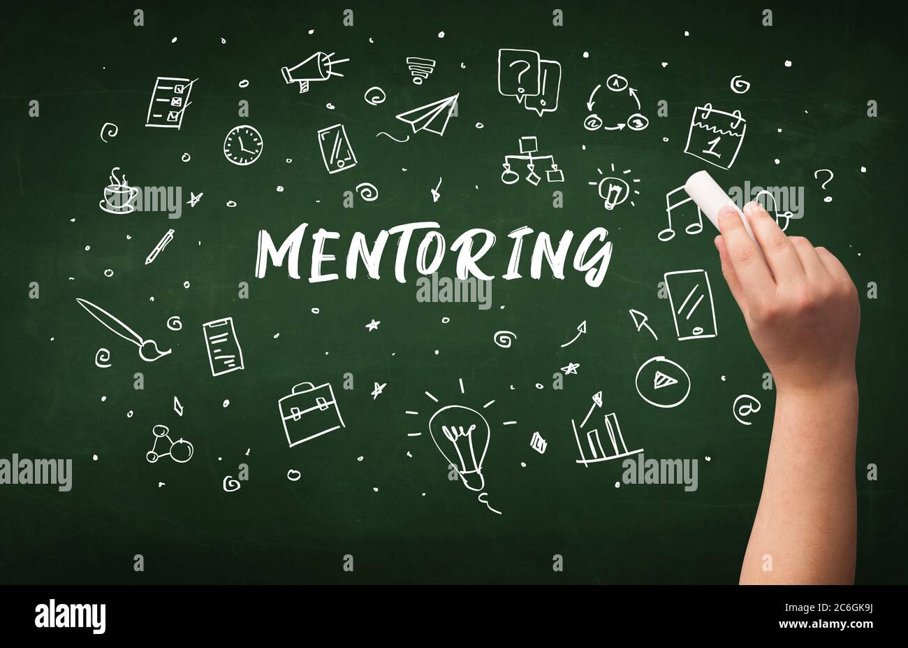 Hand drawing MENTORING inscription with white chalk on blackboard ...
