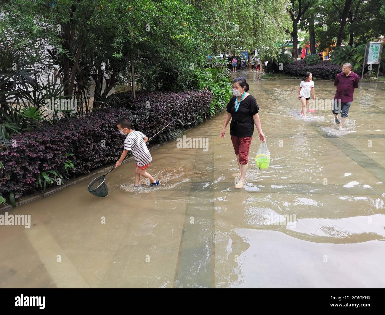 People fish on the street in the city ponding caused by heavy rain in ...