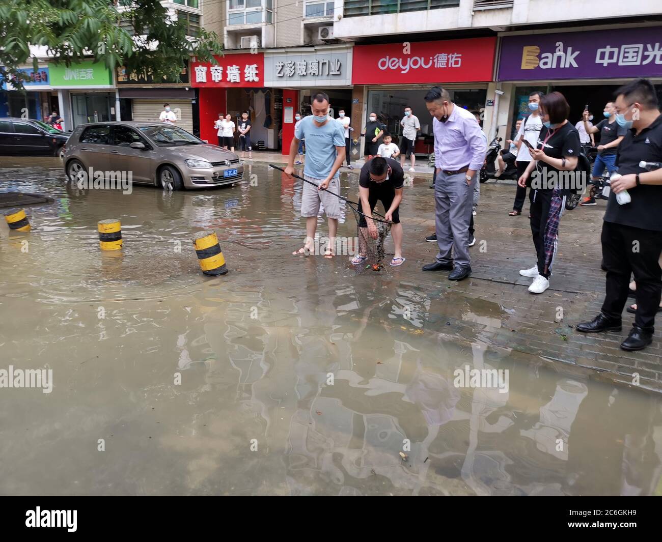 People fish on the street in the city ponding caused by heavy rain in ...