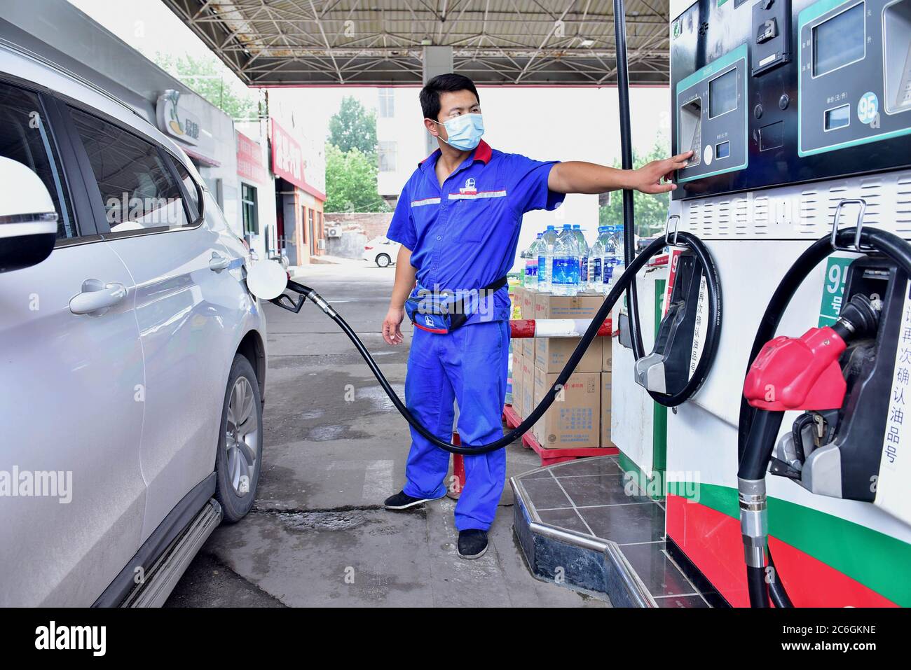 A worker is adding oil to a car at a gas station in Shijiazhuang city ...