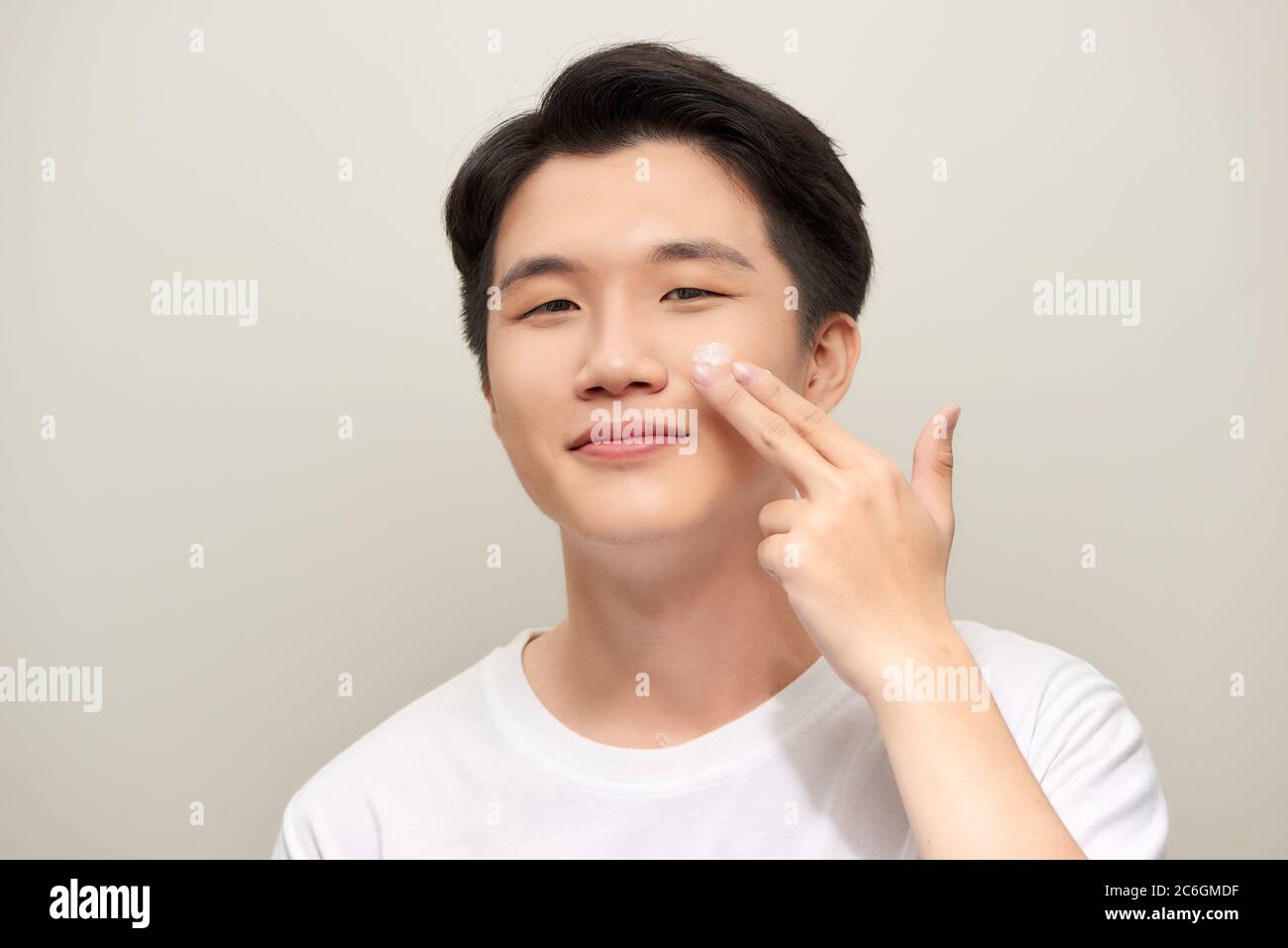 Handsome man applying eyes cream close up portrait studio on white ...