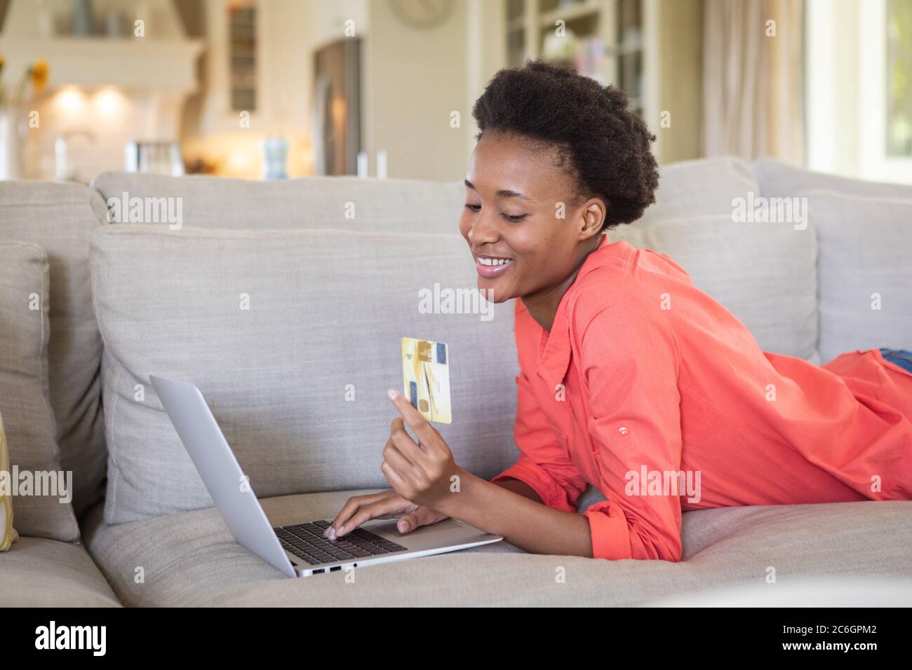 Woman with credit card using laptop while laying on the couch Stock ...