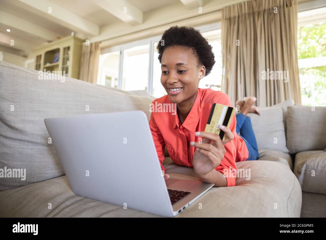 Woman with credit card using laptop while laying on the couch Stock ...