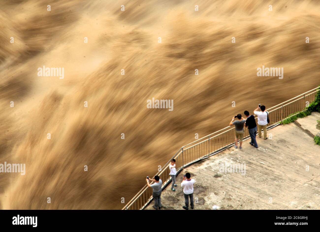 Visitors stands on the shore to enjoy the grand scenery of water ...