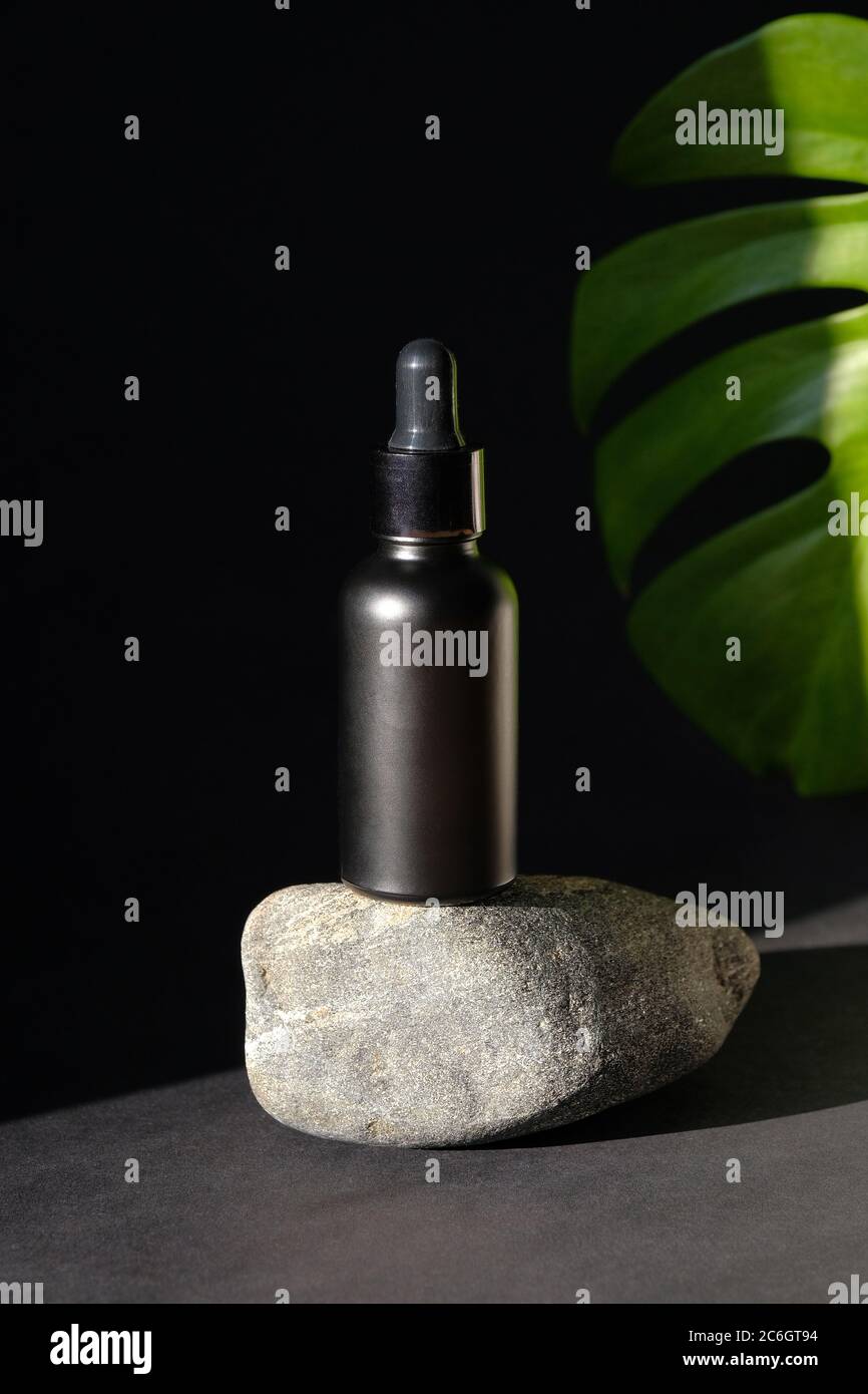 Black dropper bottle with organic essential oil for hair on stone and ...