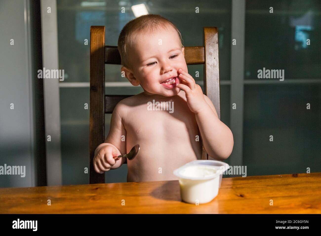 Adorable baby boy eating cottage cheese from spoon, healthy milk snack ...