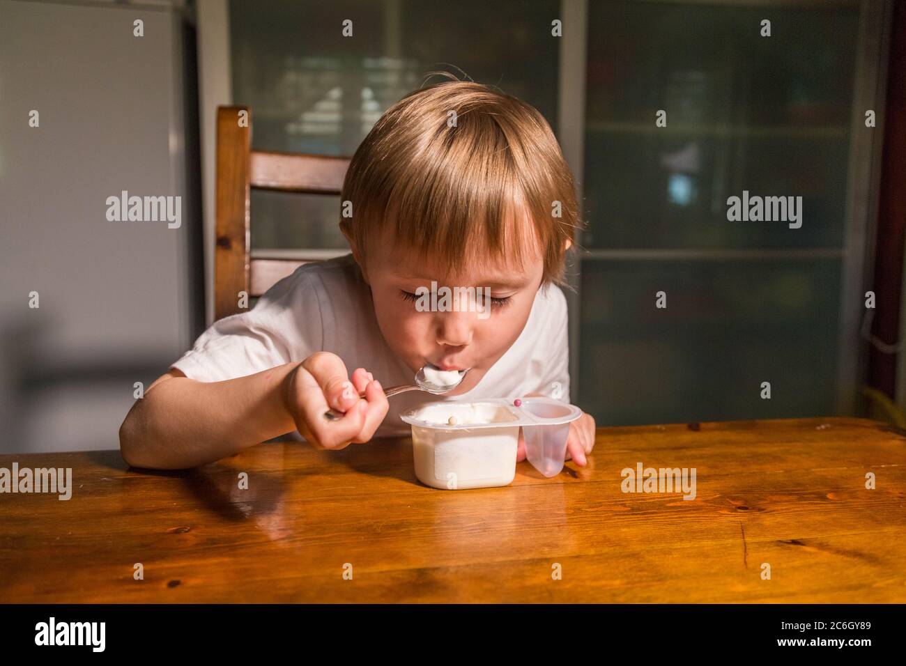 Adorable baby girl eating cottage cheese from spoon, healthy milk snack ...