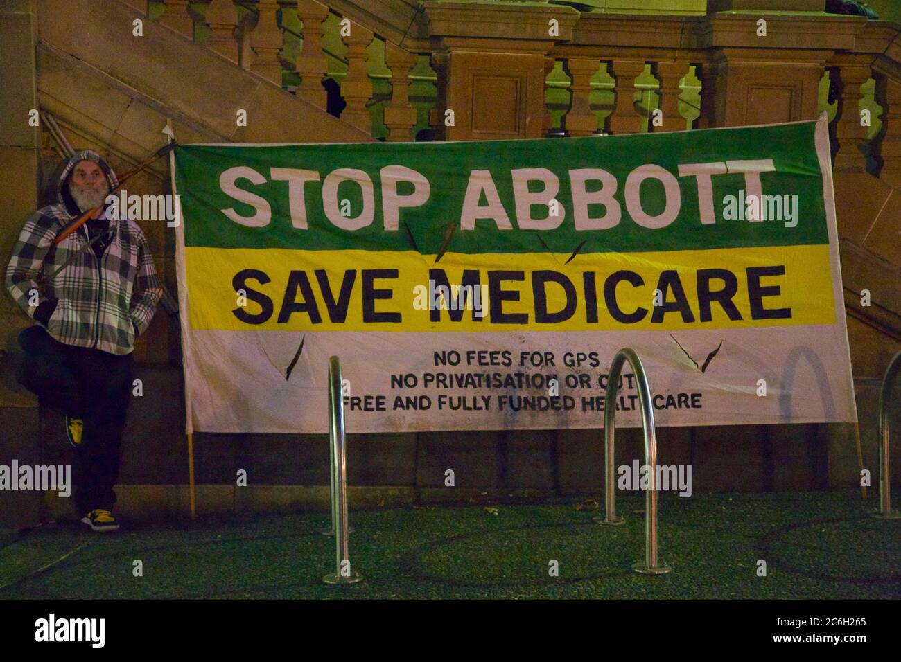 A banner at the rally says, ‘Stop Abbott. Save Medicare’ at the ‘Bust ...