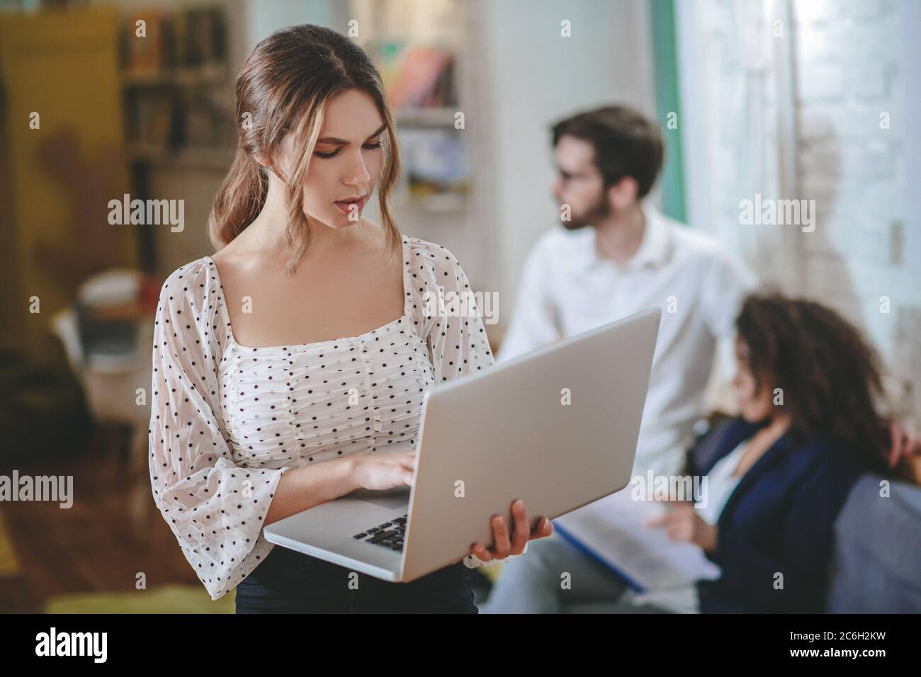 Serious involved girl standing with laptop working Stock Photo - Alamy
