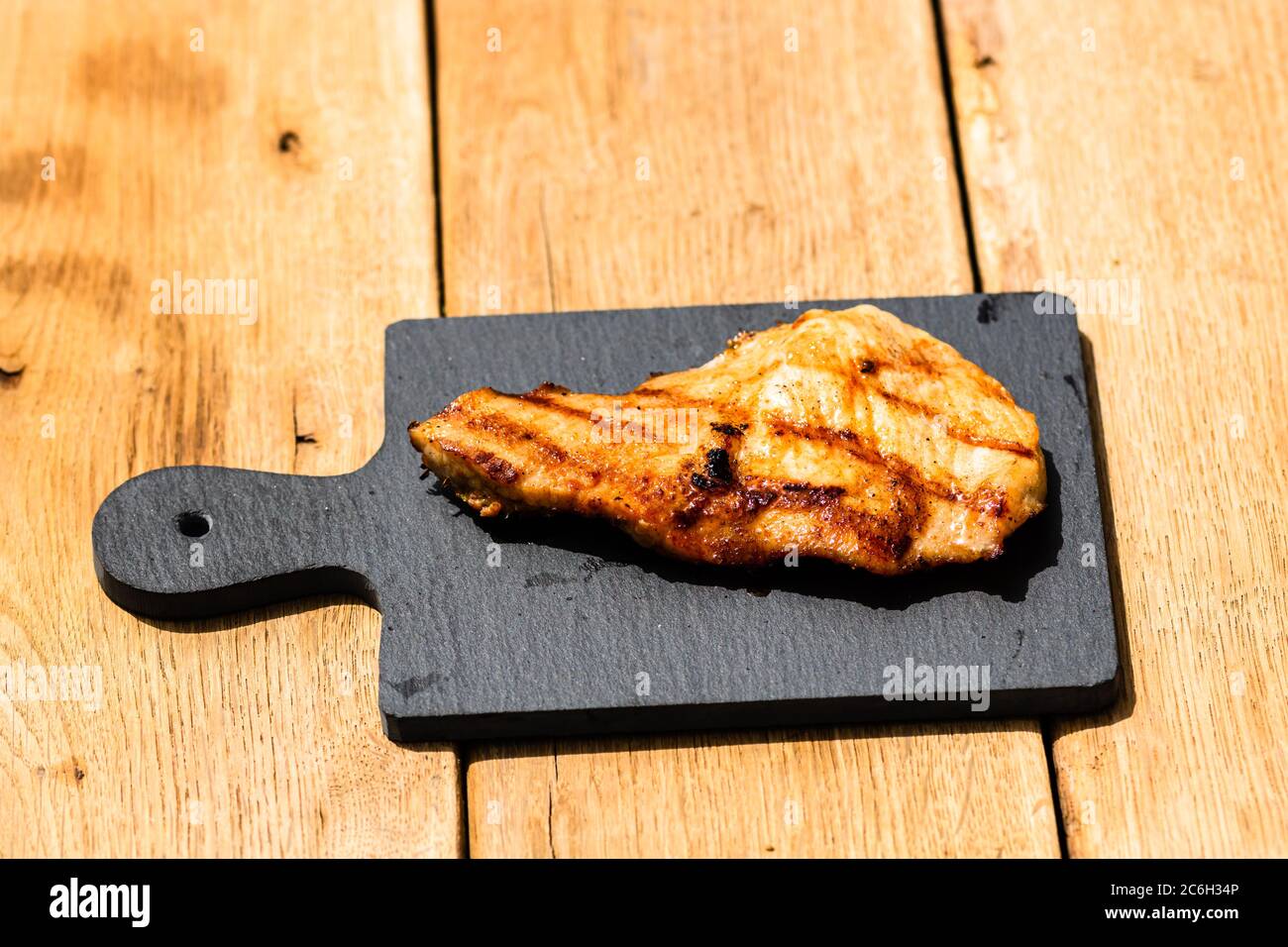 Close up of grilled steak on small black chopping board isolated ...