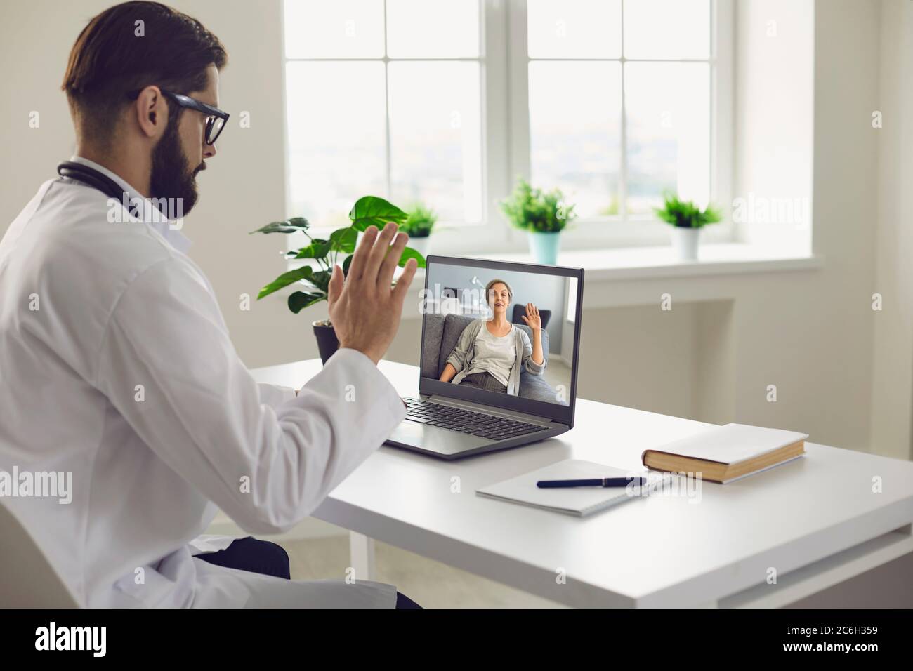 Remote medical consultation. A male doctor consults a woman has a video ...