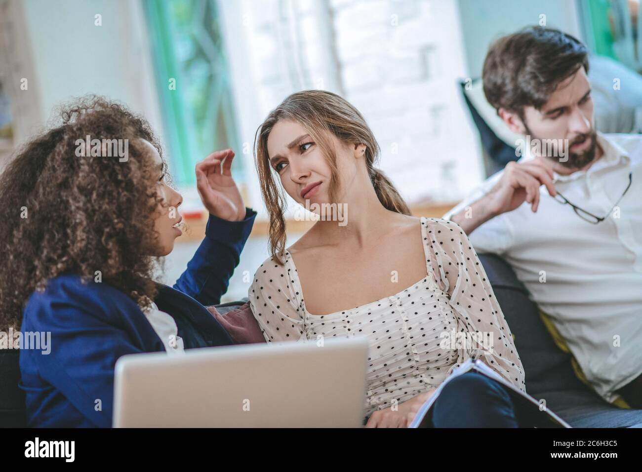 Sad girl and friend sympathizing with her, boyfriend nearby Stock Photo ...